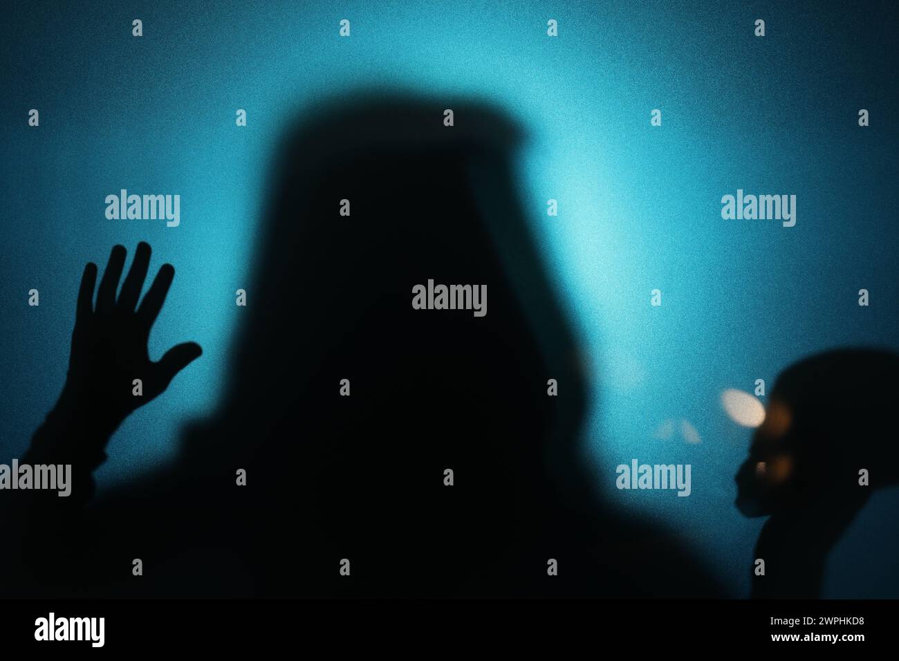 Silhouette of ghost behind glass against blue background Stock Photo ...