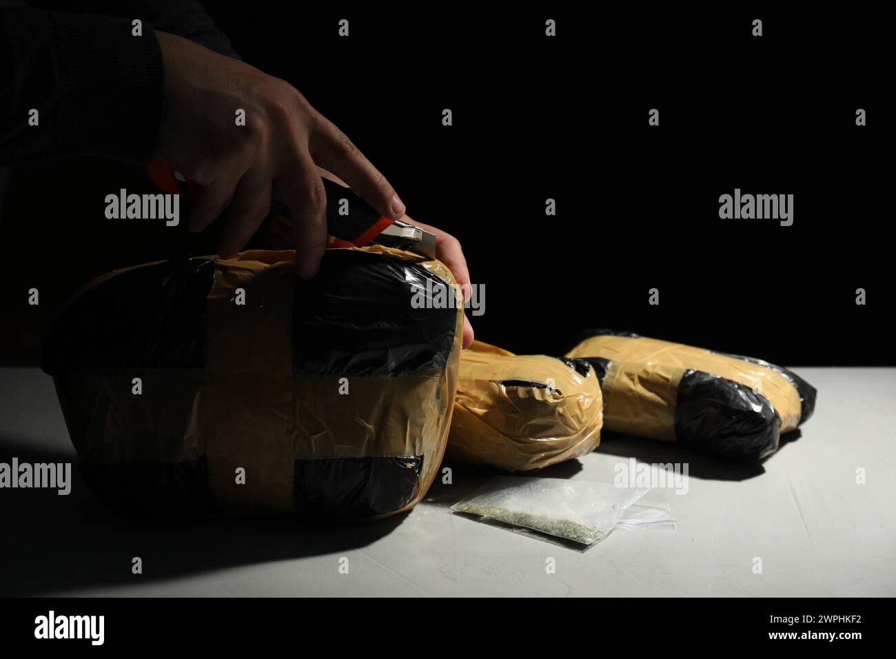 Smuggling and drug trafficking. Man opening package of narcotics with ...