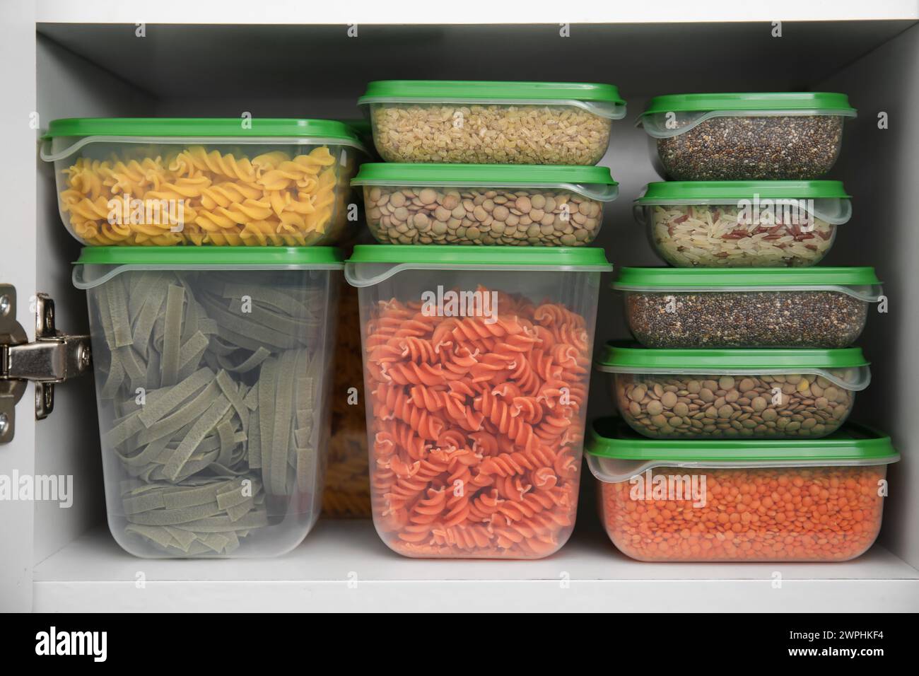 Plastic containers filled with food products in kitchen cabinet ...