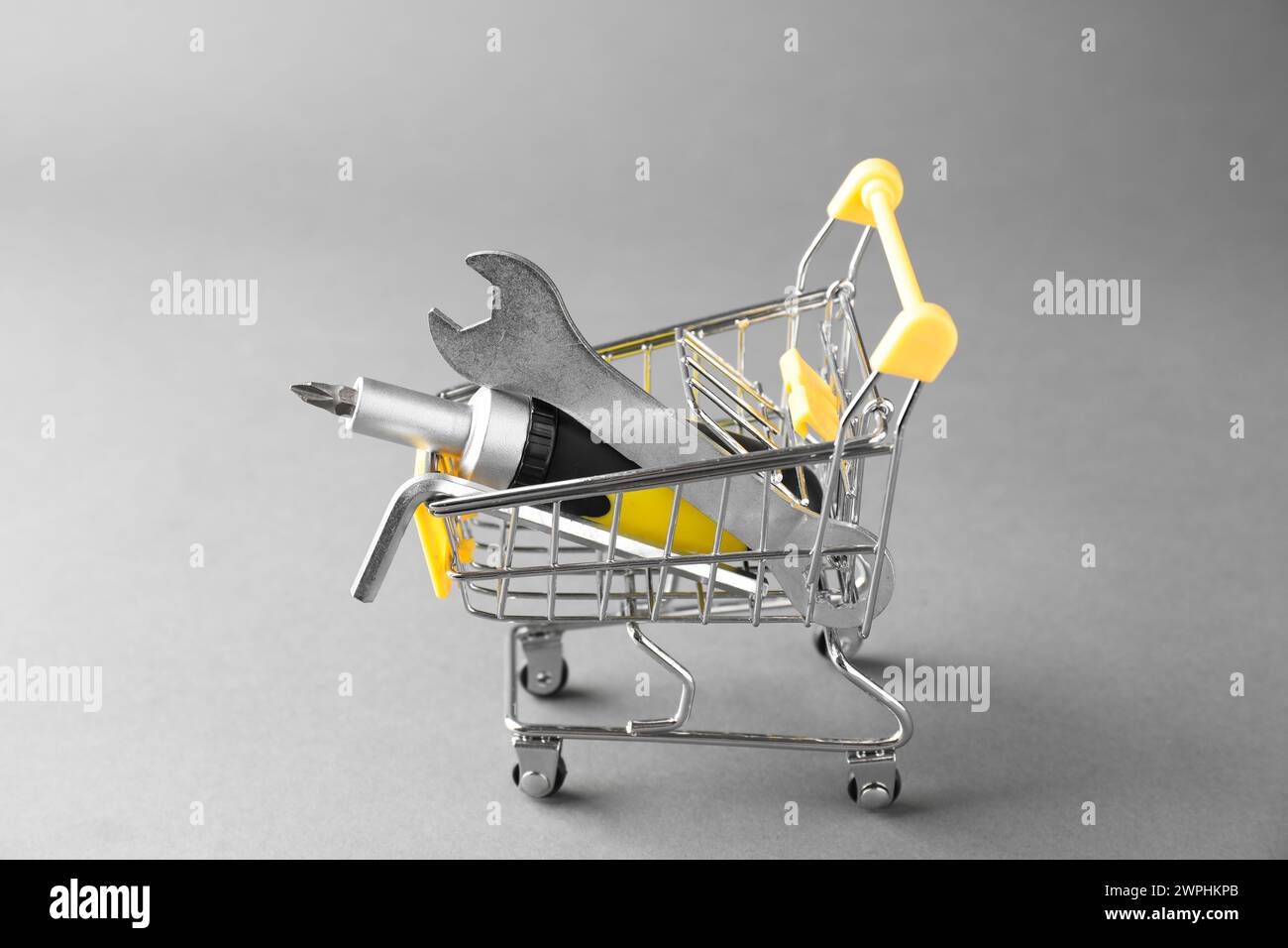 Small shopping cart with set of construction tools on grey background ...