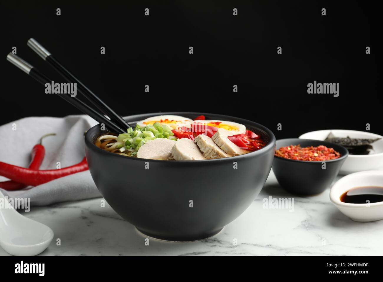 Delicious ramen in bowl on white marble table against black background ...