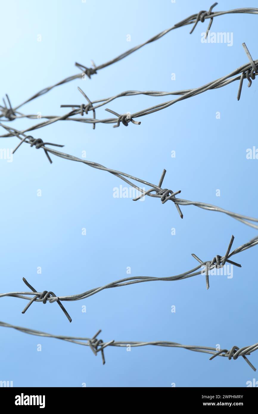 Metal barbed wire on light blue background Stock Photo - Alamy