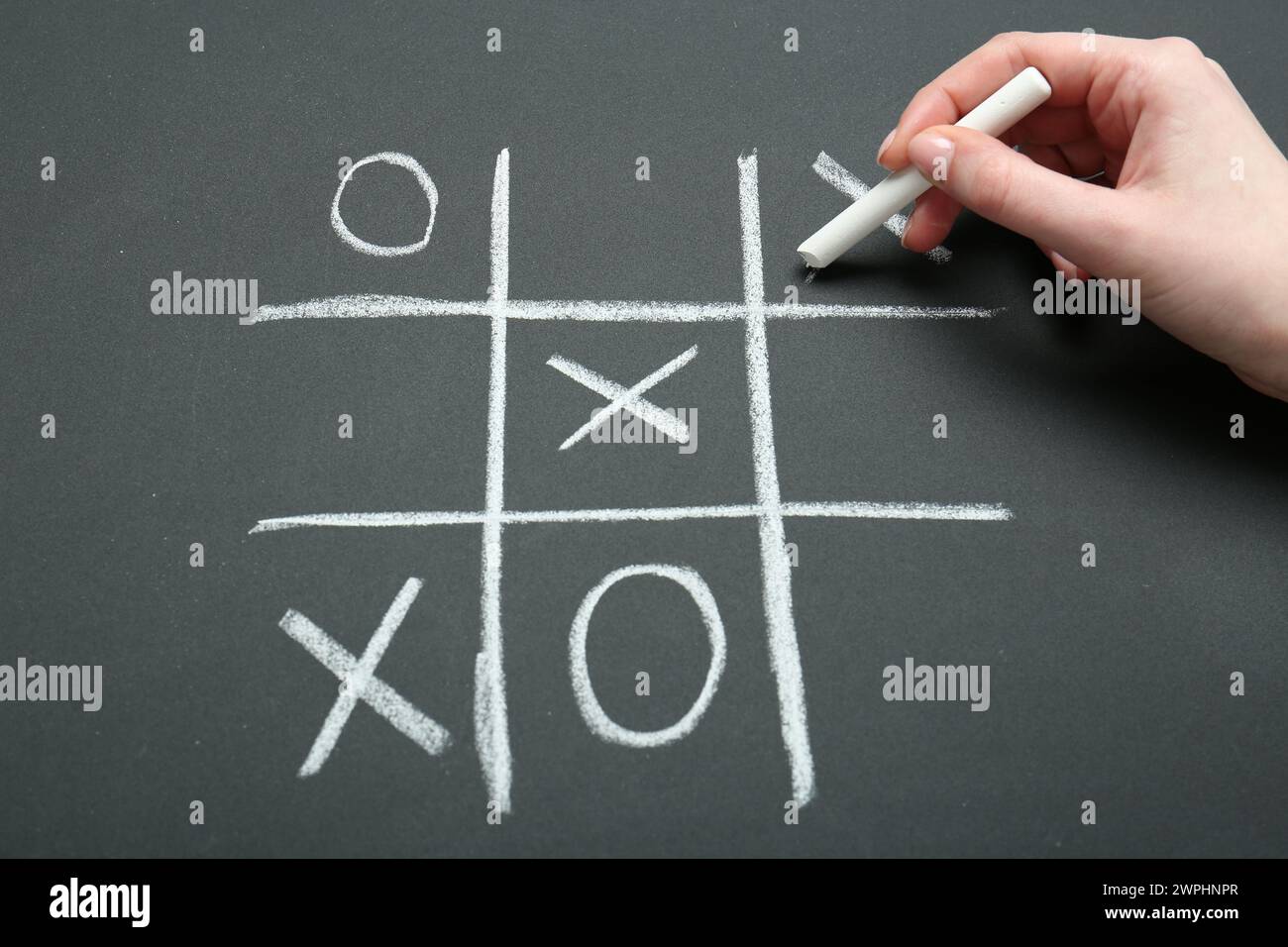 Woman playing tic tac toe on chalkboard, closeup Stock Photo - Alamy