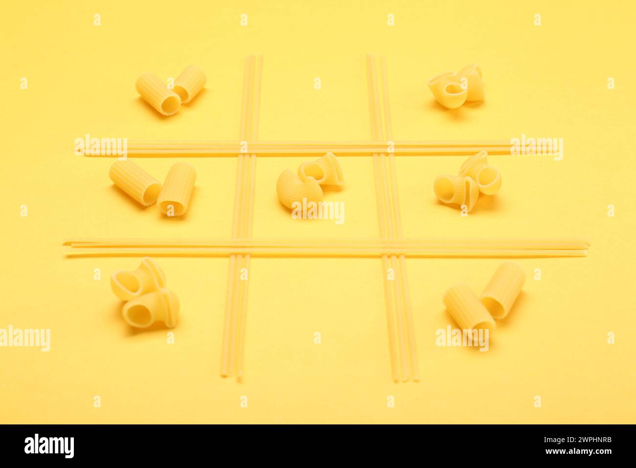 Tic tac toe game made with different types of pasta on yellow ...
