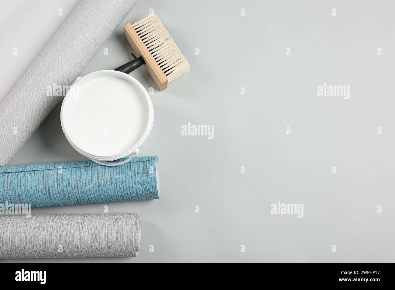 Different wallpaper rolls, brush and bucket with glue on light ...