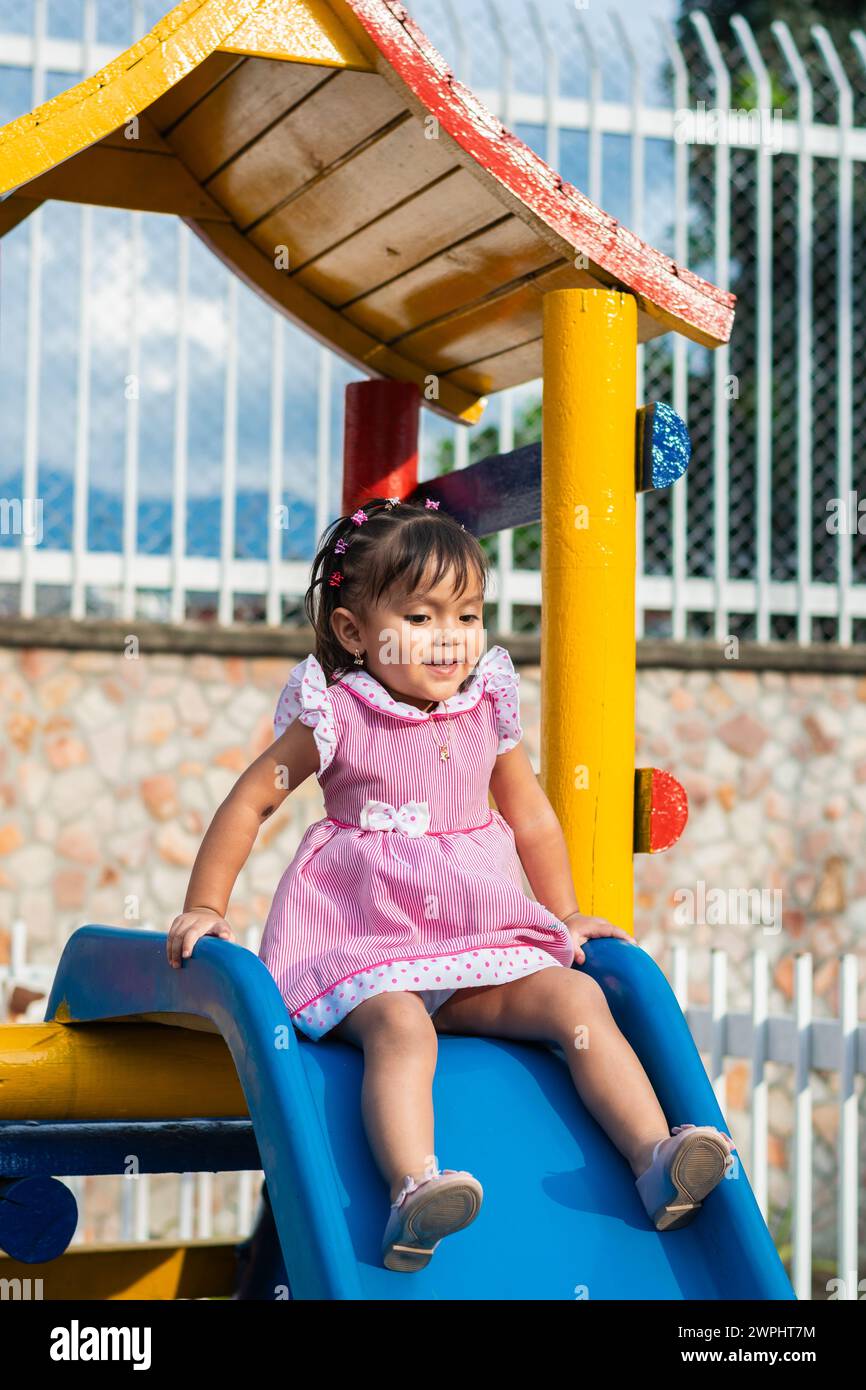 happy little latina brunette girl smiling about to go down the slippery ...