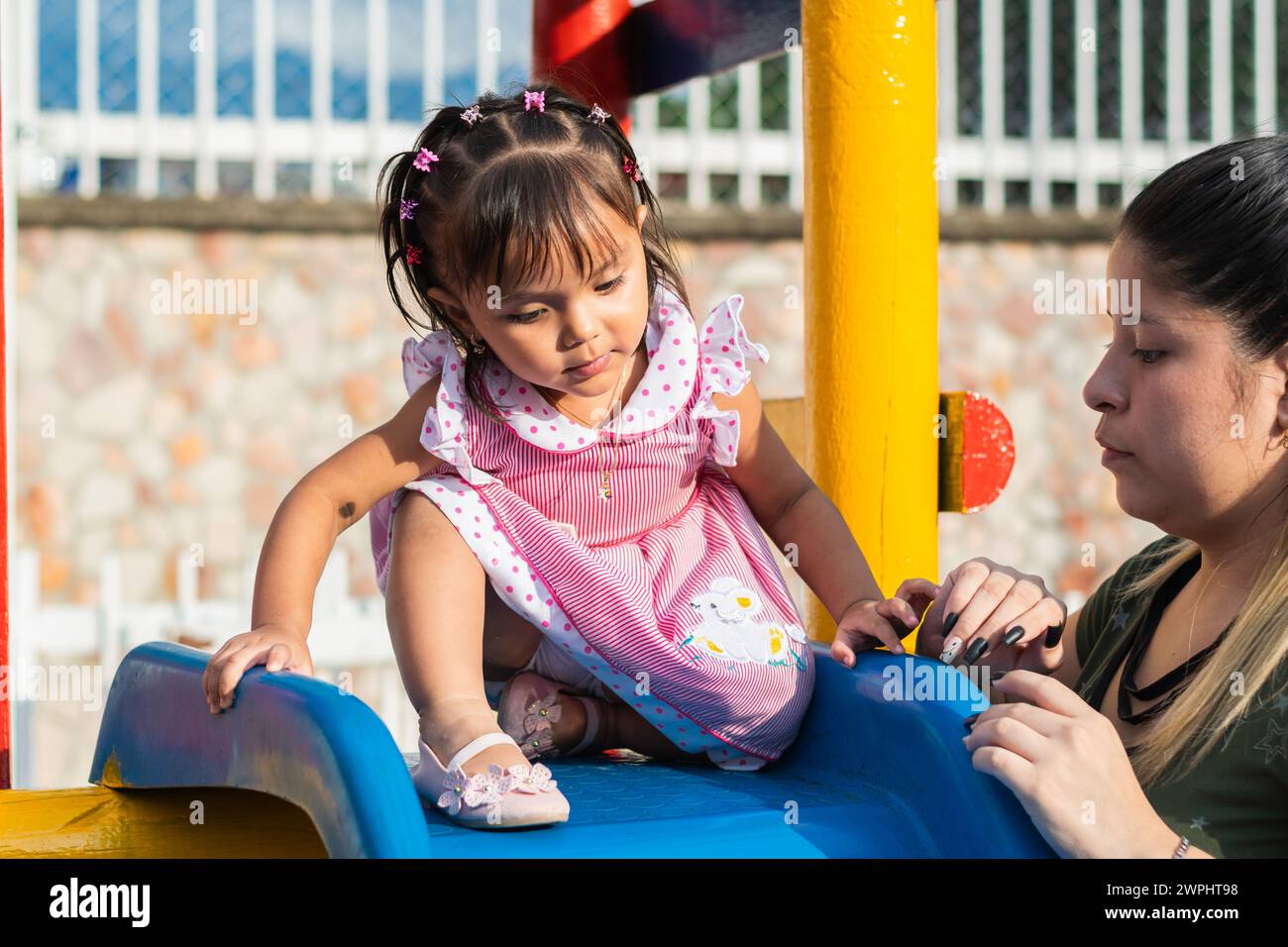 little brunette latina girl with her mother about to go down the small ...