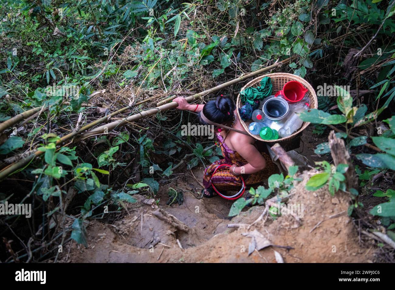 A Mro woman returns home after fetching drinking water from a mountain ...