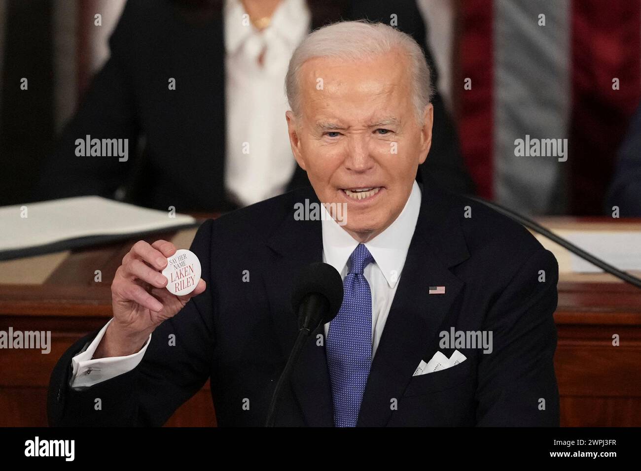 President Joe Biden holds up a Laken Riley button as he delivers the ...