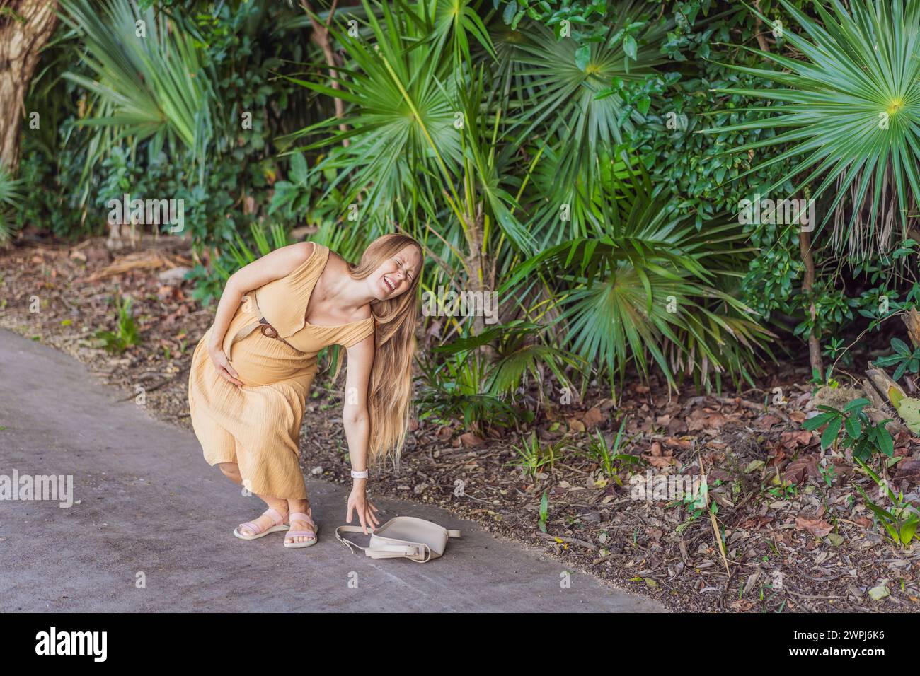 pregnant woman drops her keys and struggles to pick them up ...