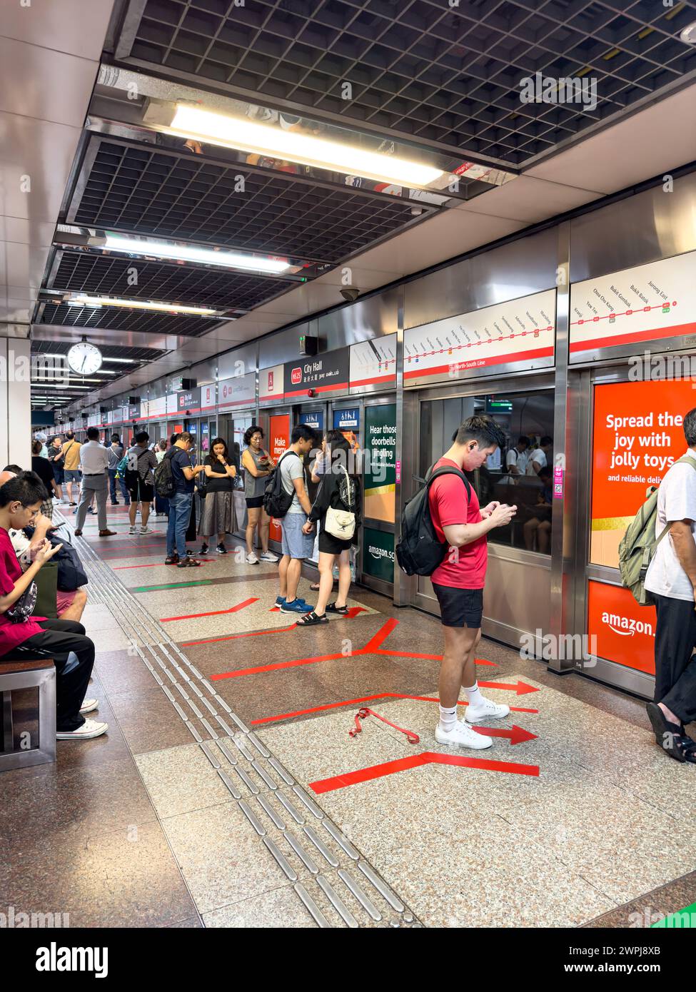 Commuters waiting to board at the City Hall station on the Singapore ...