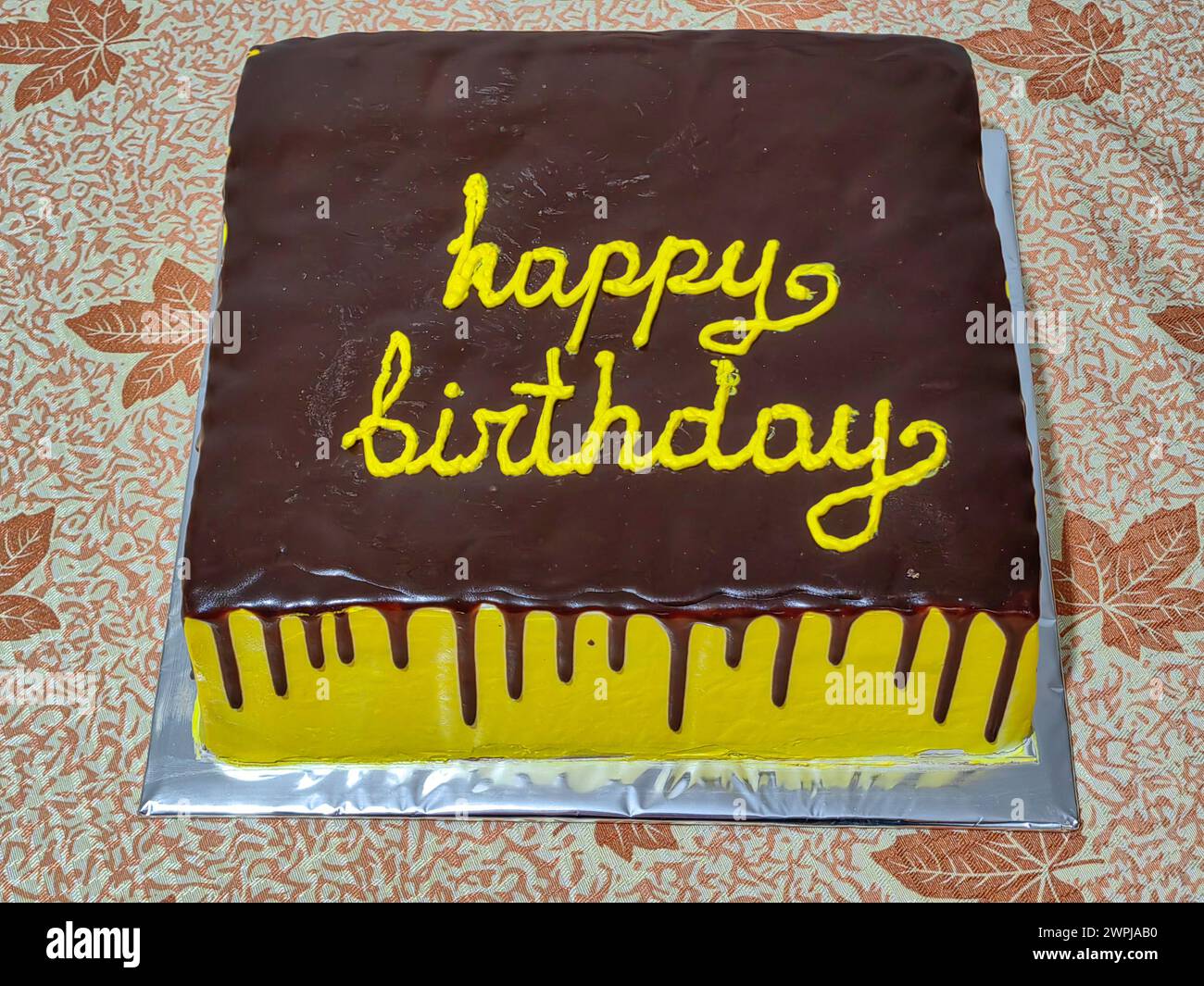 Dark chocolate delight. Happy birthday cake with yellow lettering Stock ...