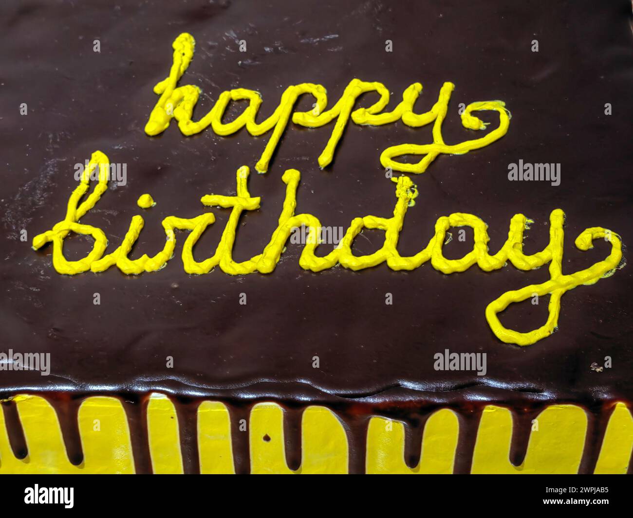 Dark chocolate delight. Happy birthday cake with yellow lettering Stock ...