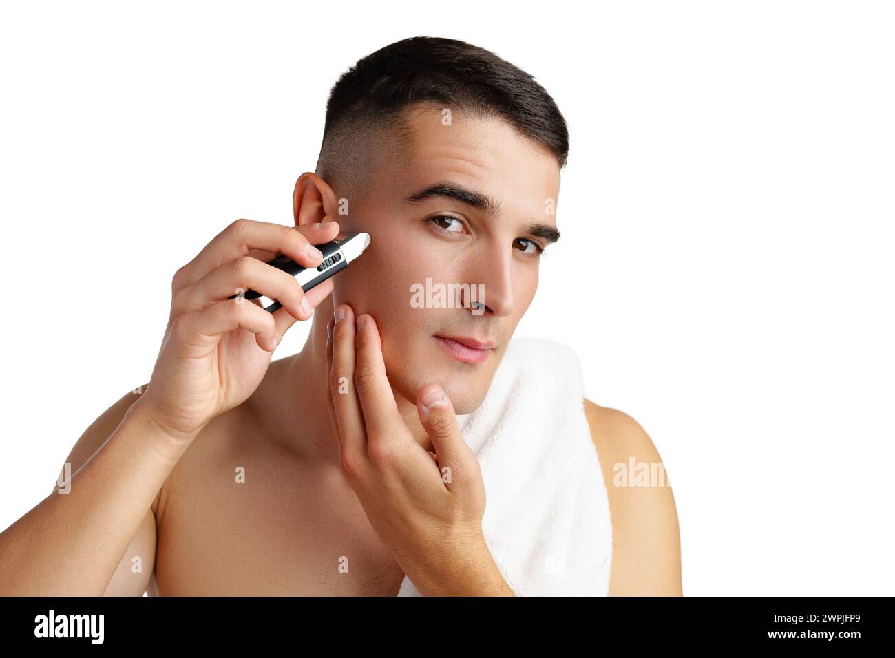 Handsome young man shaving face with electric razor on white background ...
