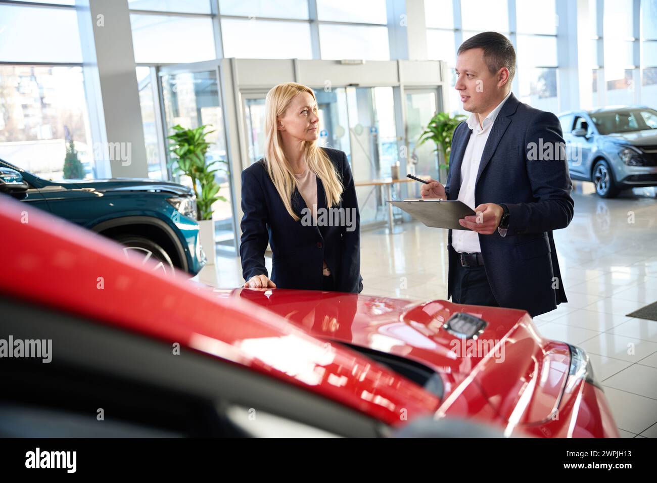 Two people talking in a car sales showroom Stock Photo - Alamy