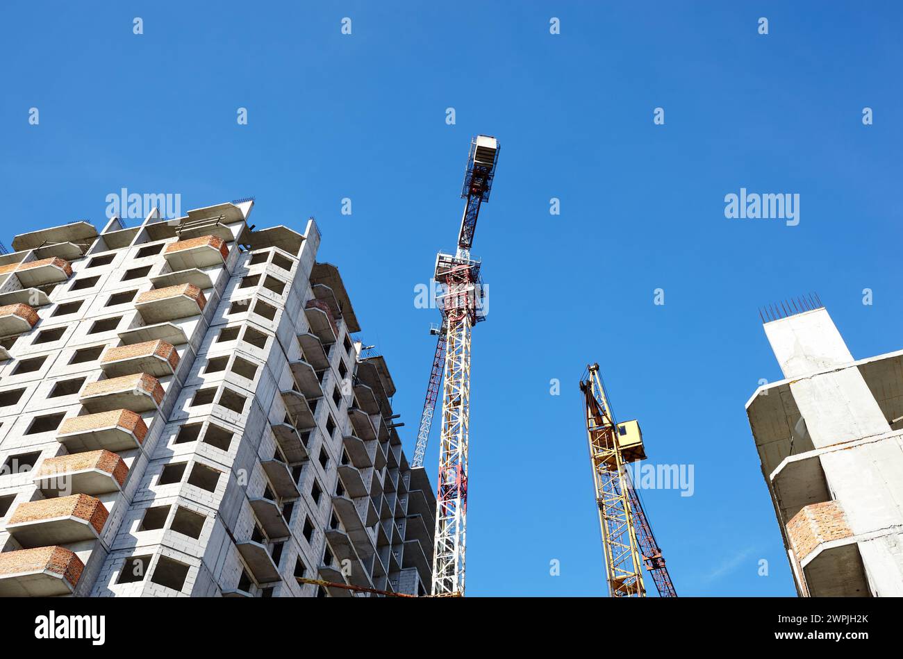 Tower cranes building a house. Concrete building under construction ...
