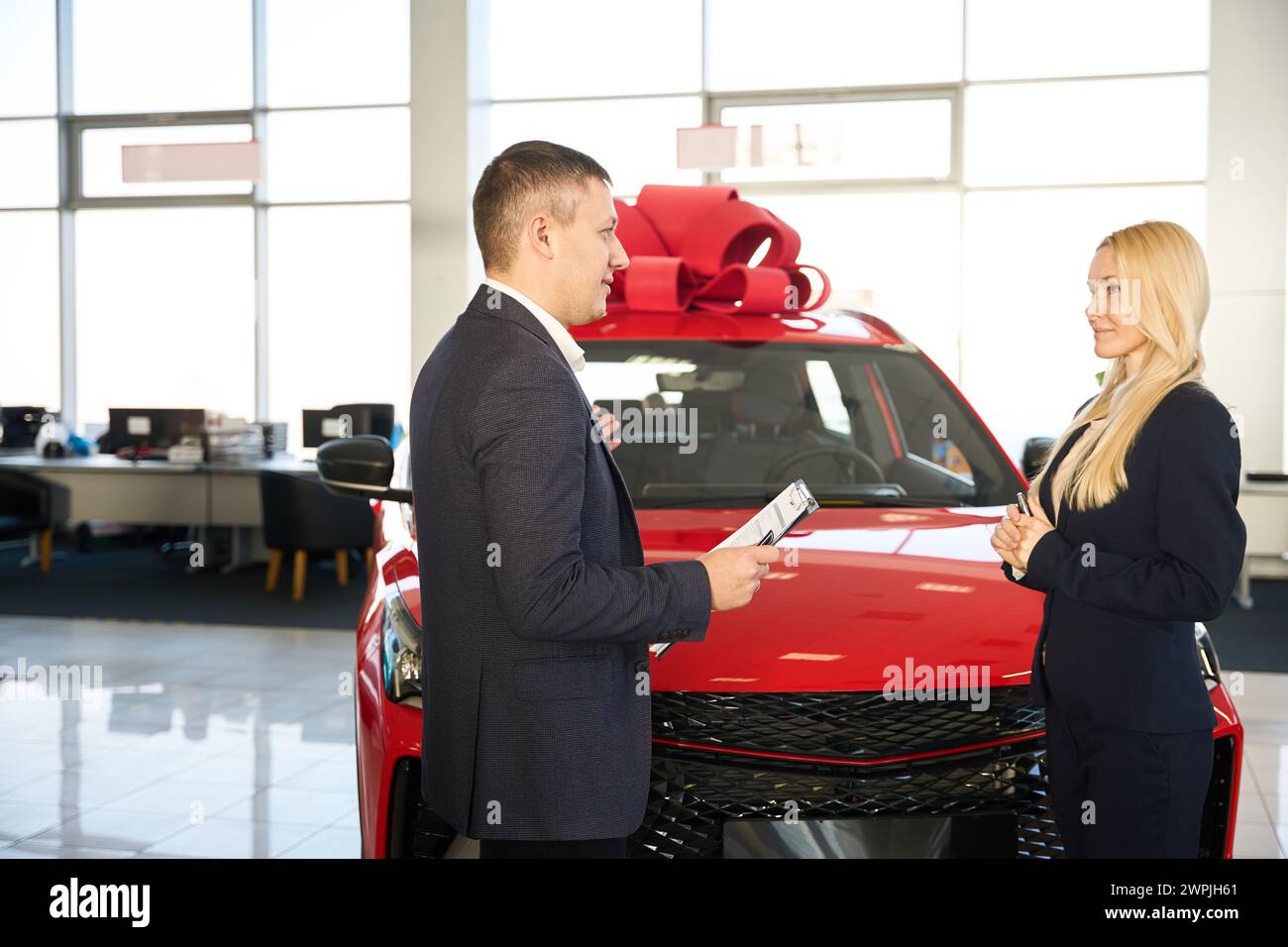 Dealer communicates with a blonde customer in a car dealership Stock ...