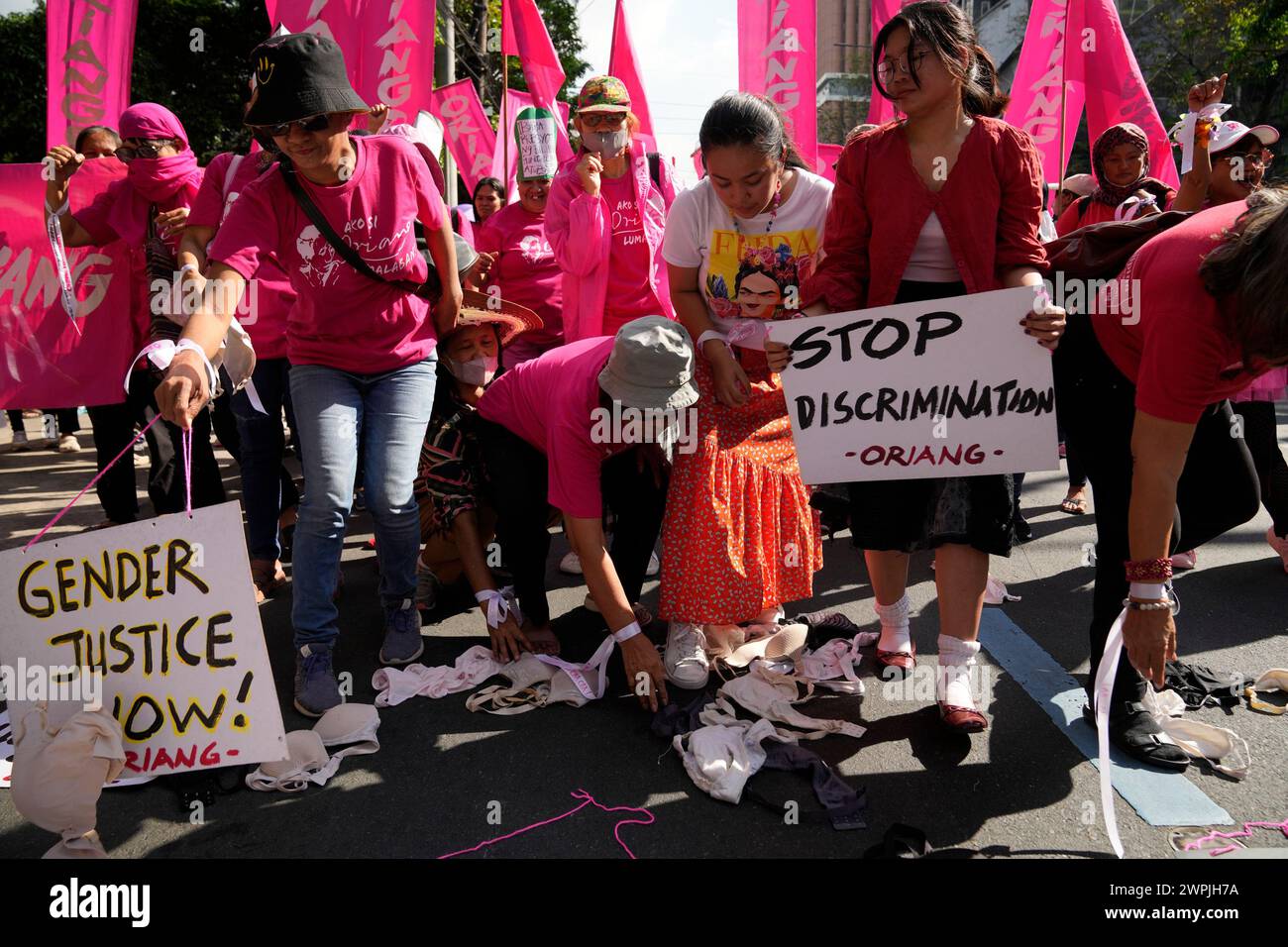 Activists hold slogans after throwing their bras on the street to ...