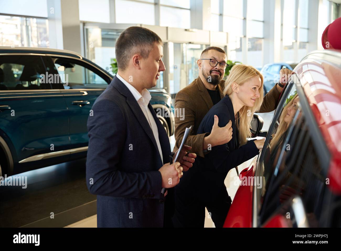 Three people are standing in a car dealership Stock Photo - Alamy