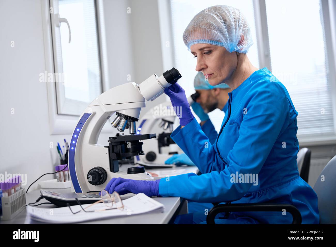 Female laboratory assistant examines biological material under a ...