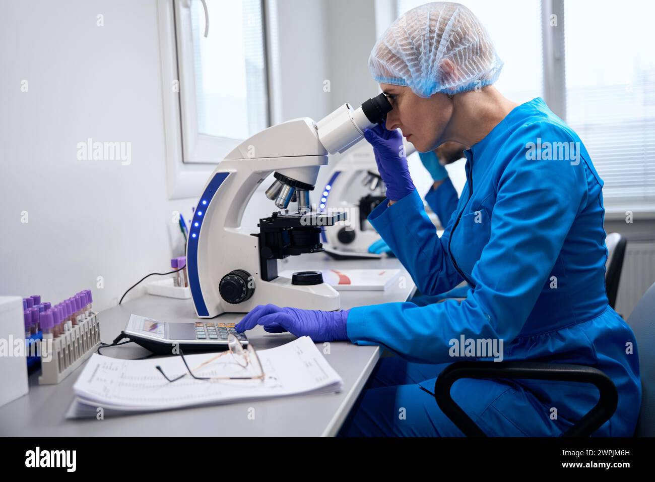 Female immunologist examines biological material under a microscope ...