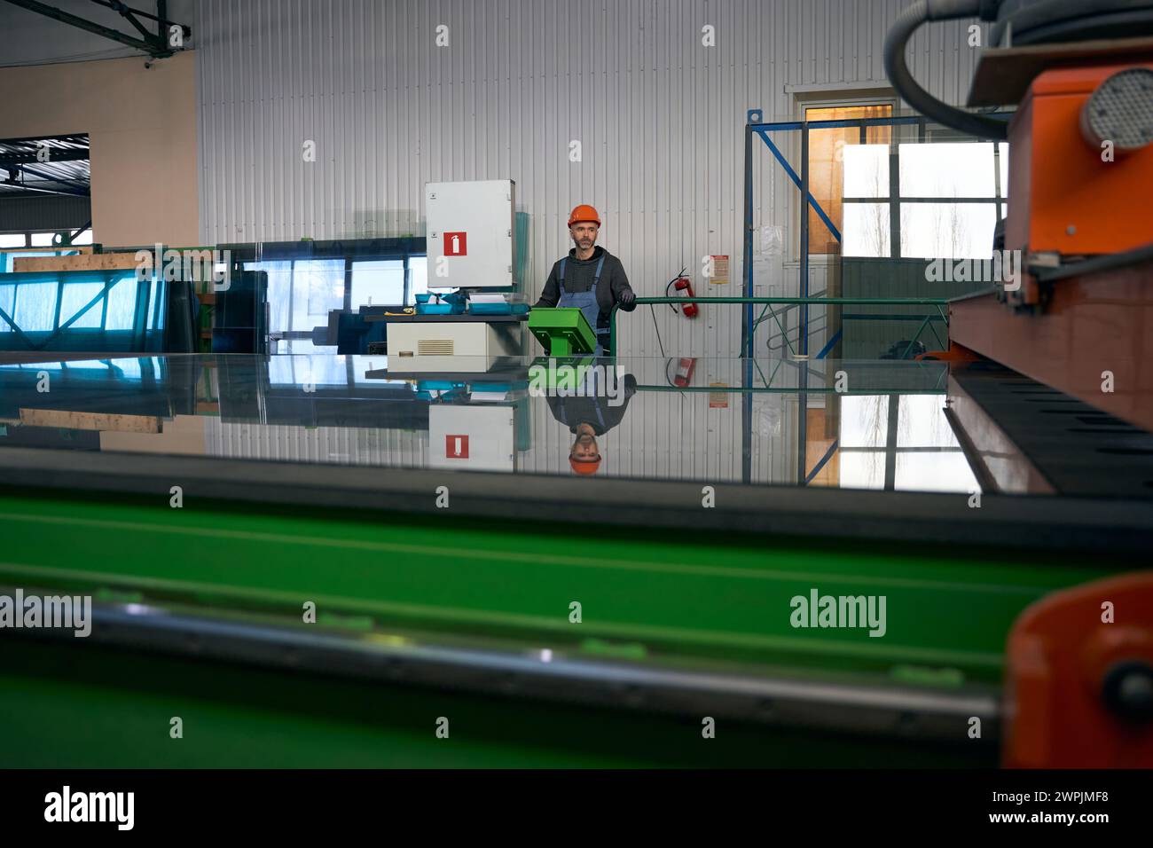 Employee uses automatic table for cutting glass in window production ...