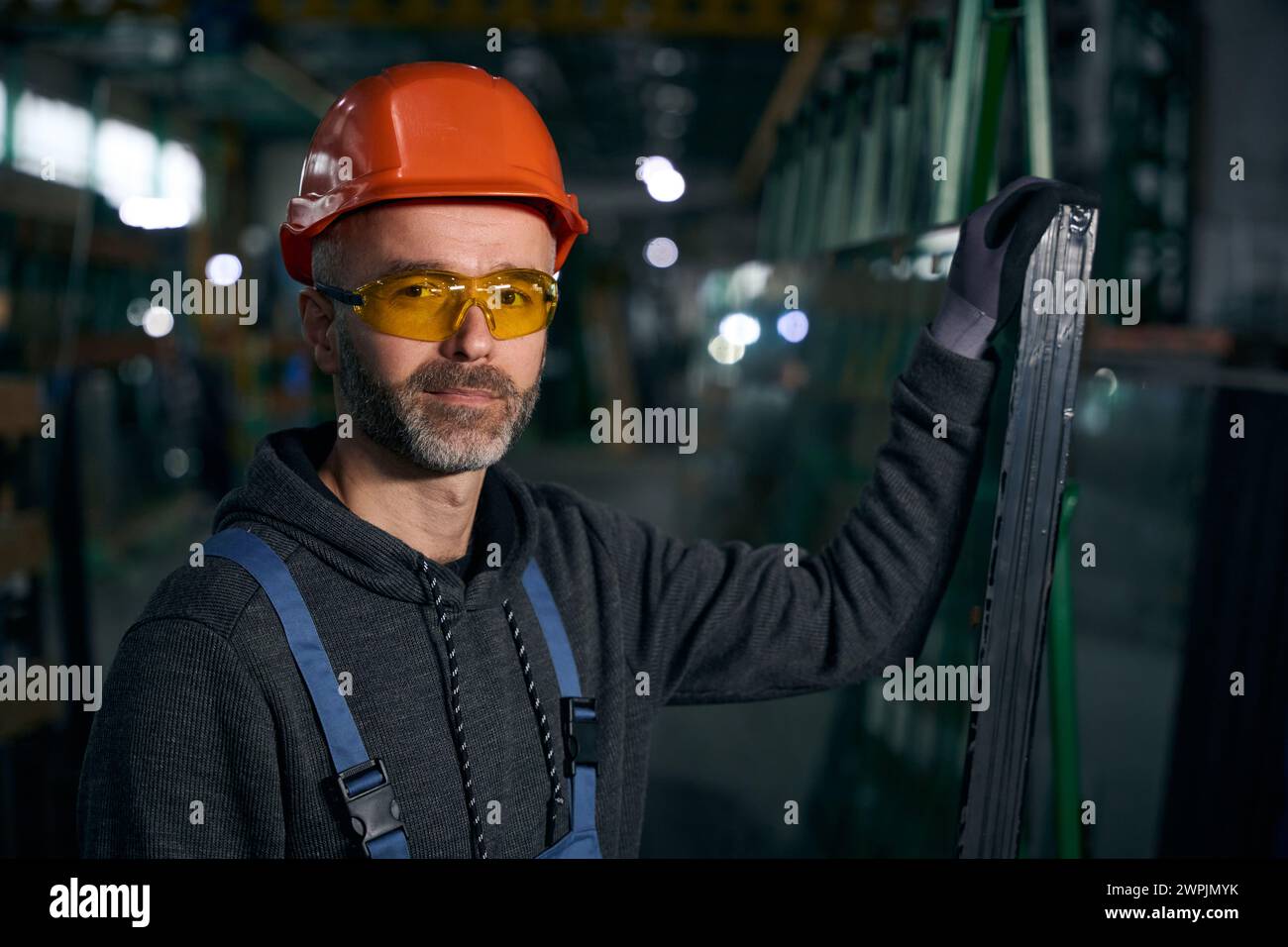 Employee works in window production with glass for double-glazed units ...