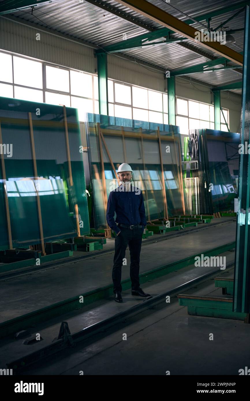 Engineer in a safety helmet stands in a production workshop Stock Photo ...