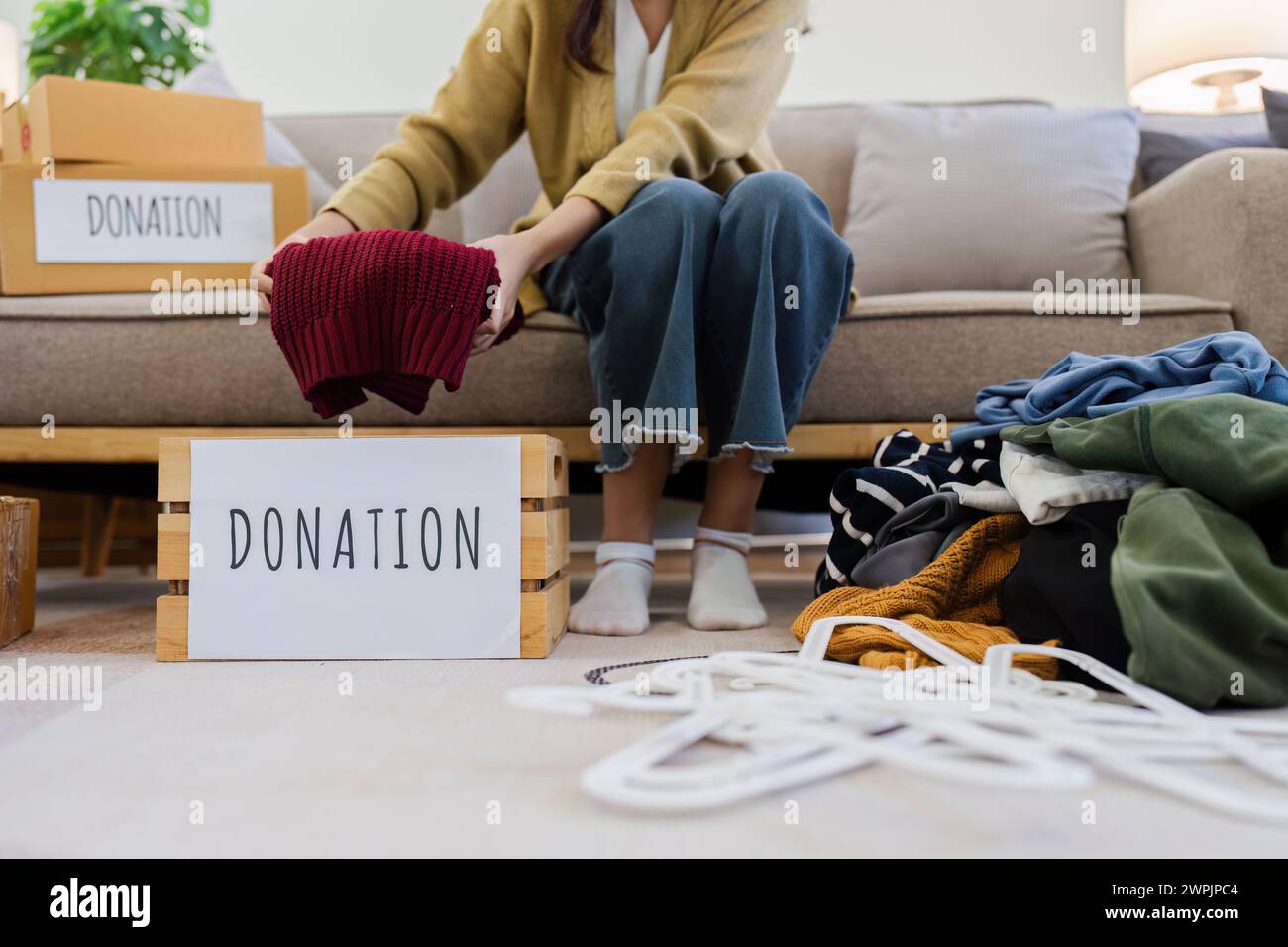 Young Asian women sit in living room sorting clothes for donation in a ...