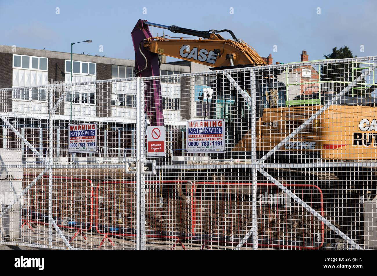 Tracked excavator behind fence with warning signs on construction site ...