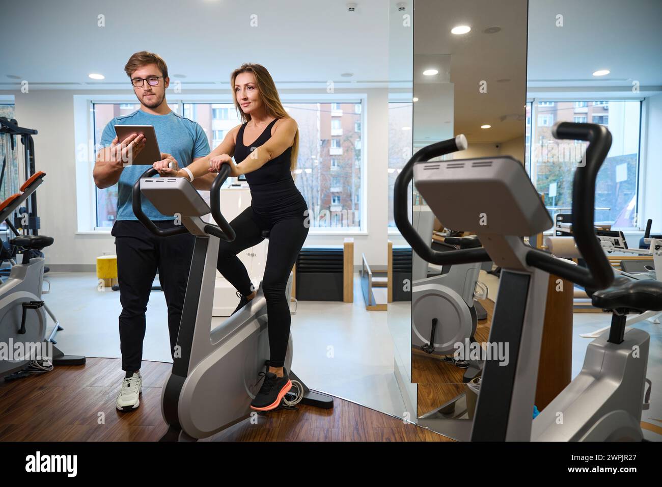 Trainer controls the clients training on an exercise bike Stock Photo ...