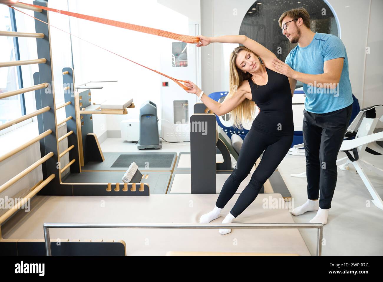 Instructor helps a woman perform stretching exercises Stock Photo - Alamy