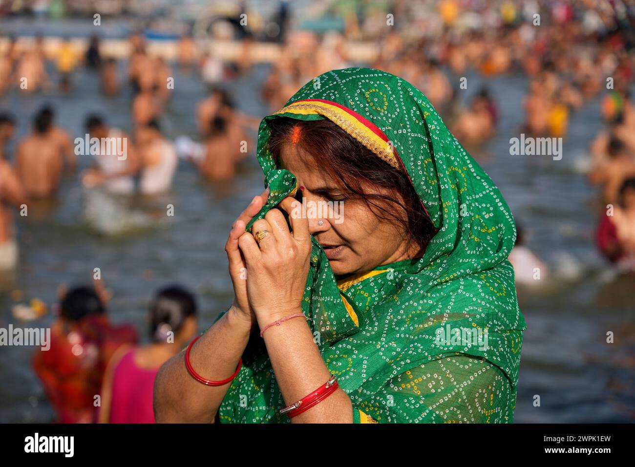 A Hindu devotee offers prayers as others take dip at the Sangam, the ...