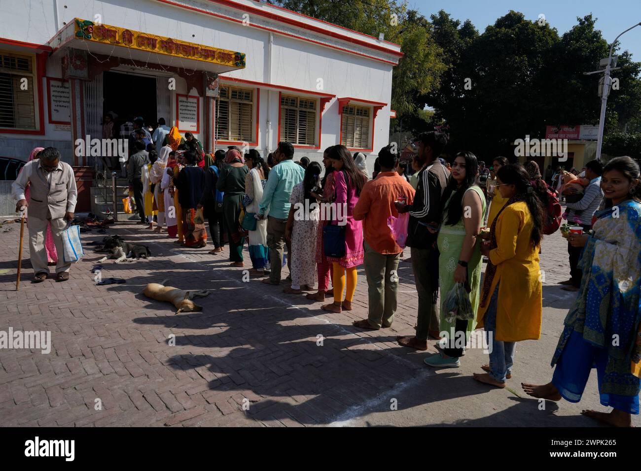 Hindu devotees stand in a queue to offers prayers at a temple during ...