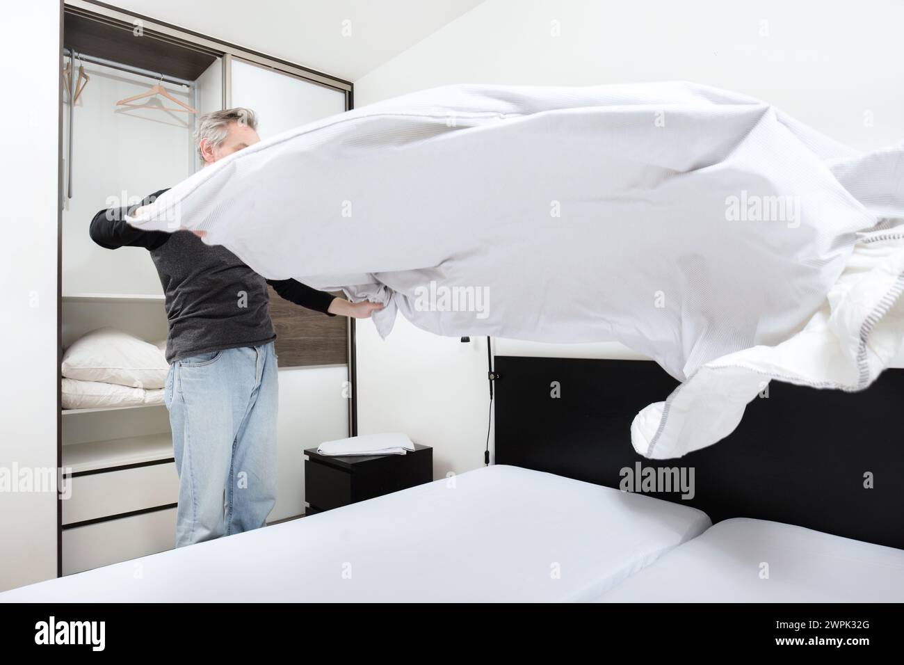 Older man working in bedroom on making bed Stock Photo - Alamy