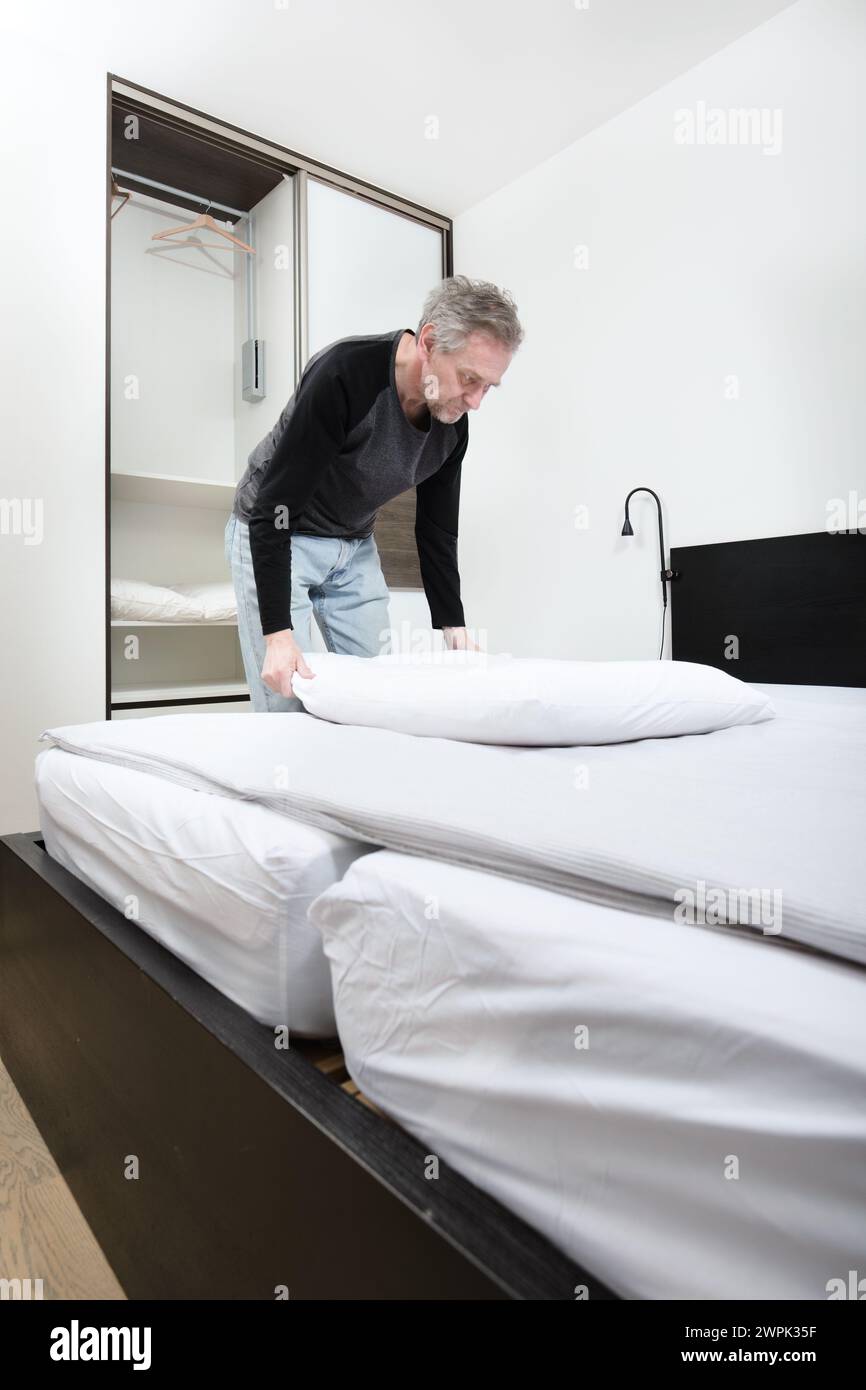 Older man working in bedroom on making bed Stock Photo - Alamy