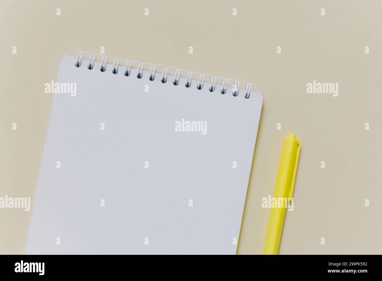 Notebook with blank page and yellow pen on light yellow background ...