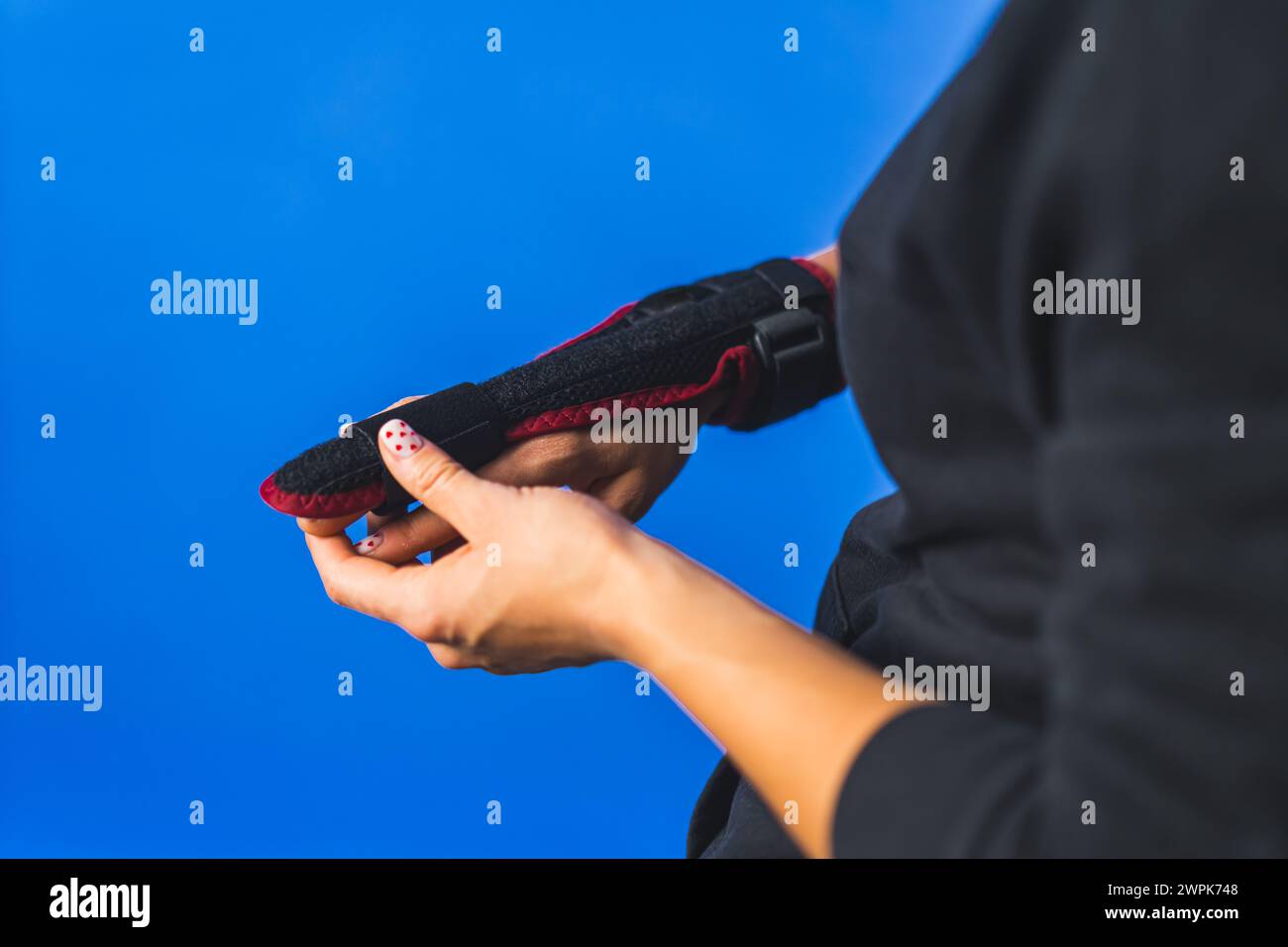 woman adjusting a splint on her middle finger, injured finger blue ...