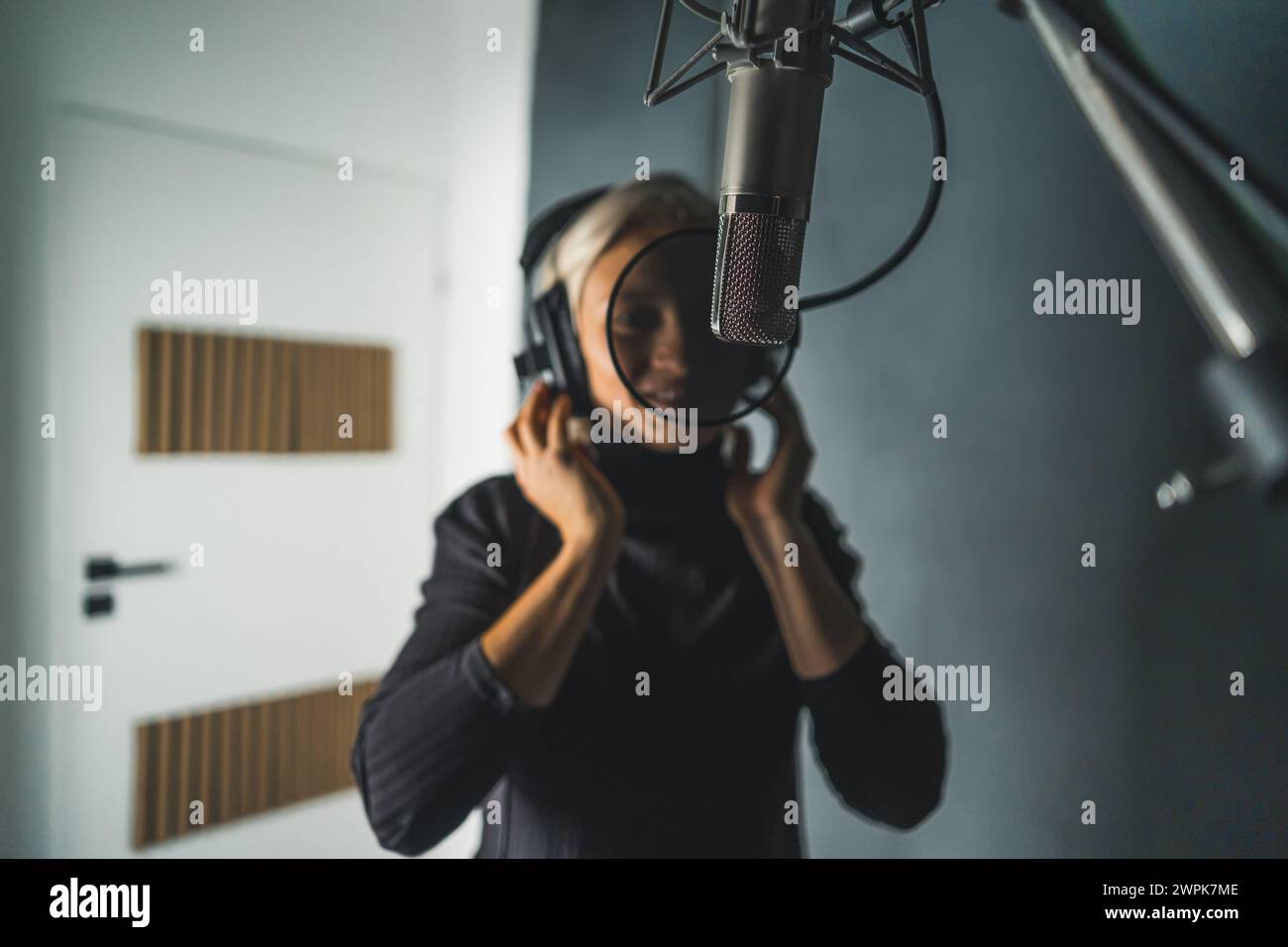 a young woman speaking a podcast or singing into the studio microphone ...