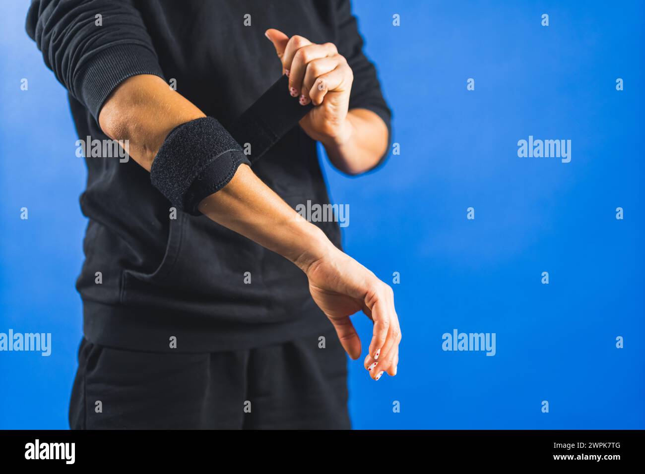 a person wrapping an elbow support brace to reduce pain, blue ...