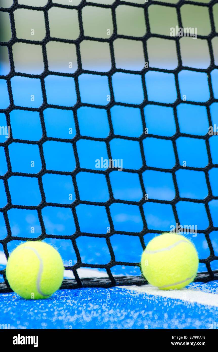 two balls next to the net of a paddle tennis court, racket sports ...