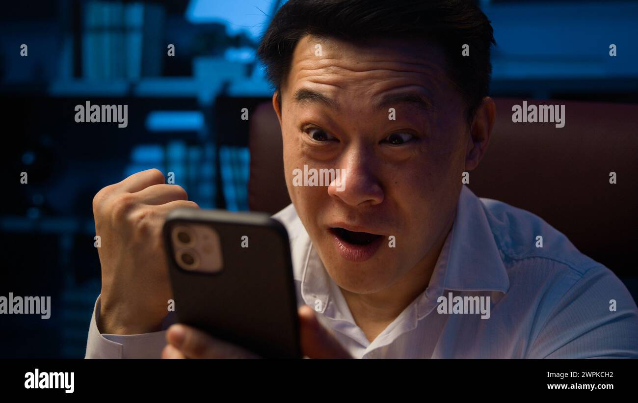 Happy smiling excited winner Asian man victory with phone win shout ...