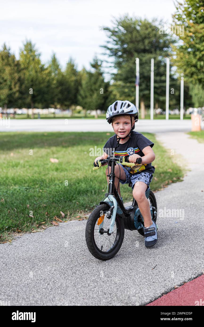 A young boy riding on his bicycle in summer with a helmet on Stock ...