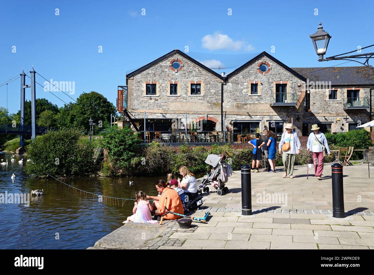 Family sitting on the east quay of the River Exe with a restaurant to ...