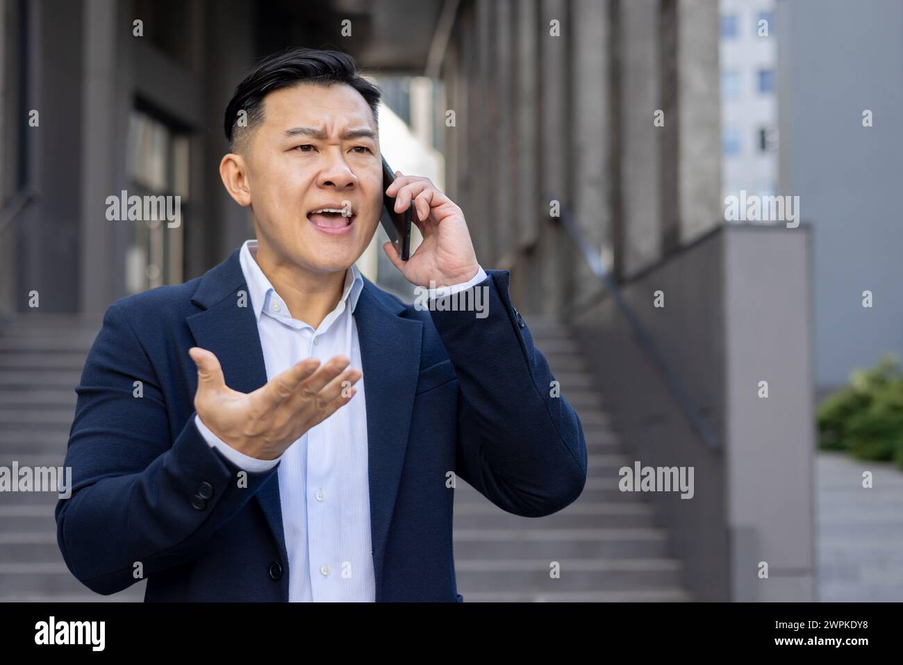 An agitated professional man in a formal suit communicates over a cell ...