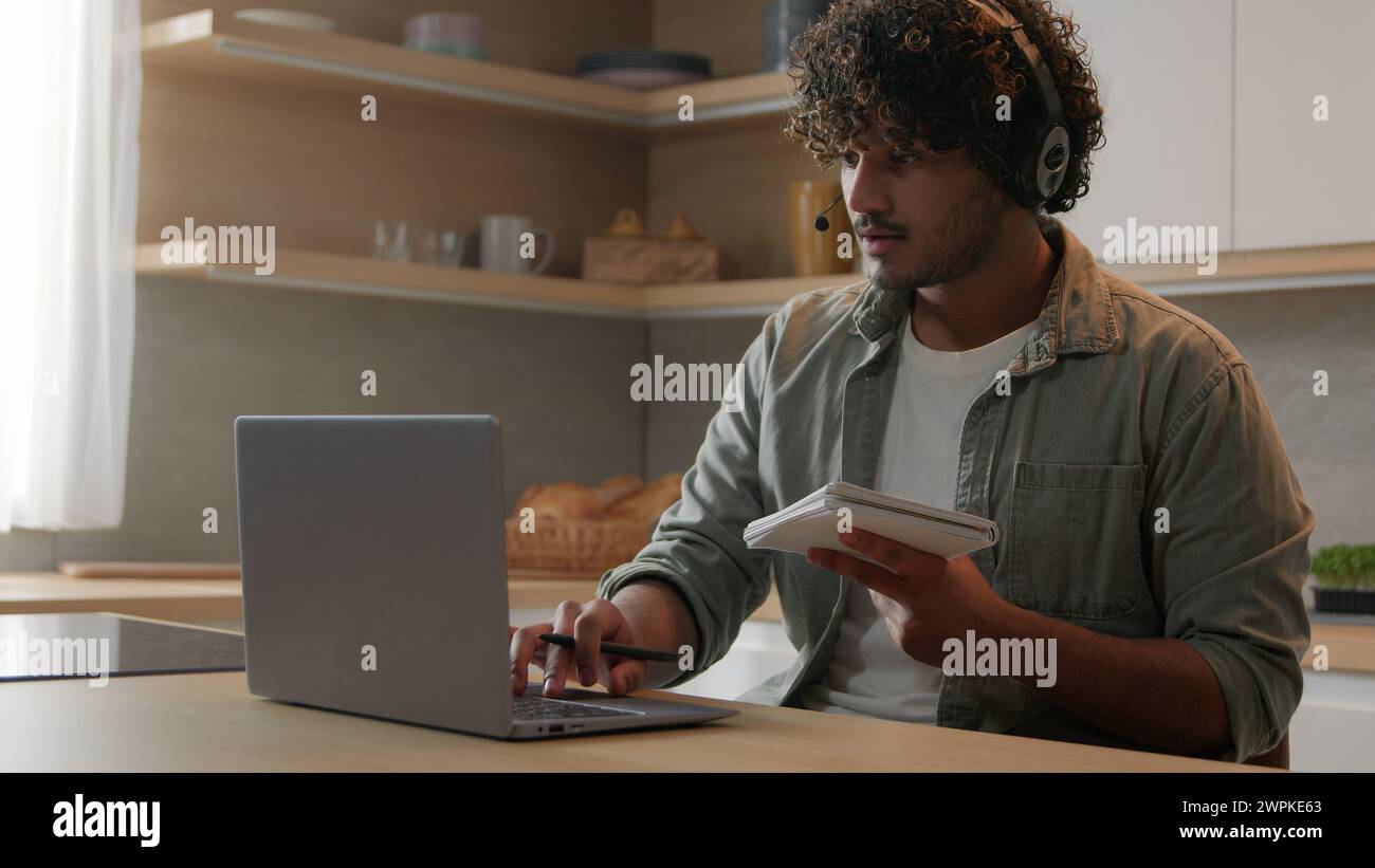 Indian man in headset look app pc browsing typing laptop write ideas ...
