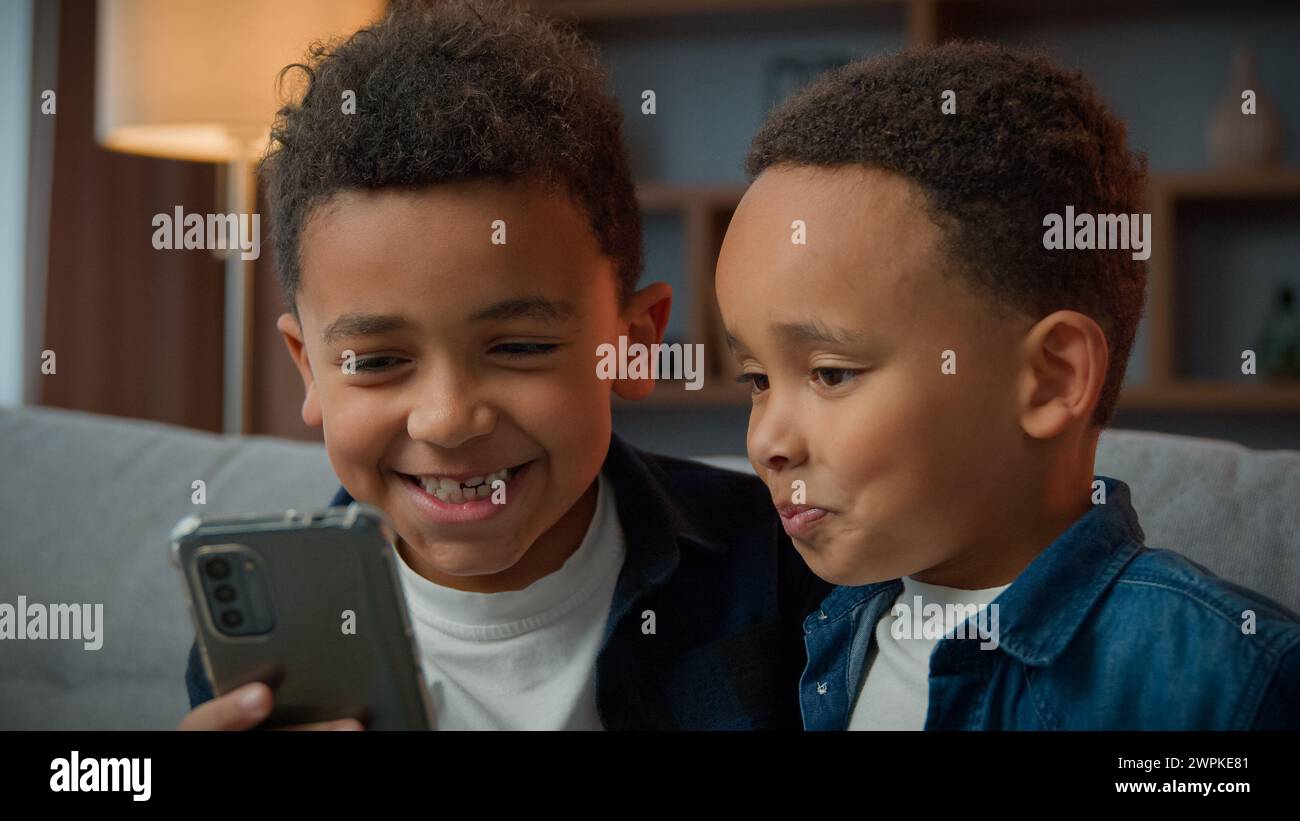 Two African American little boys brothers laughing browsing mobile ...