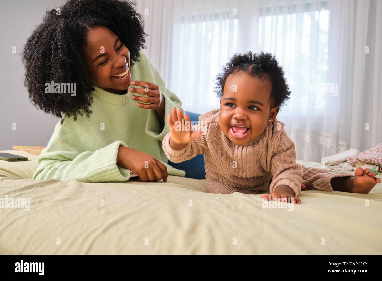 Happy Cuban mother and toddler daughter laughing in bed Stock Photo - Alamy