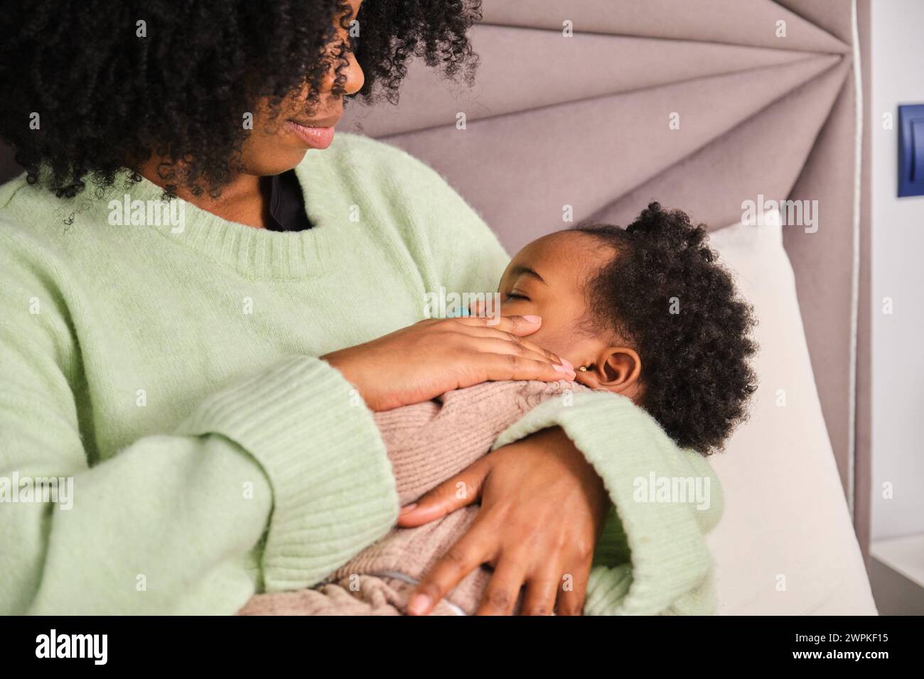 Cuban mother cradle her toddler daughter for sleep on bed Stock Photo ...
