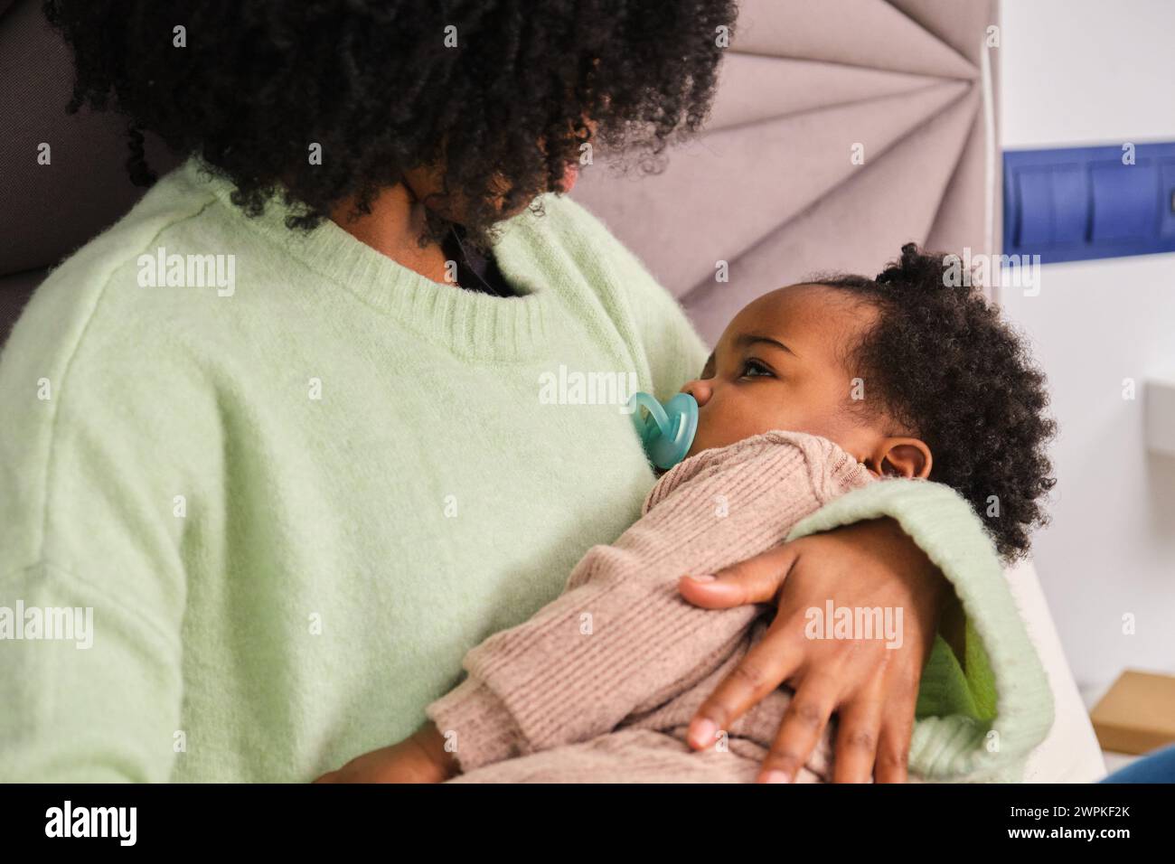 Cuban mother cradle her toddler daughter for sleep on bed Stock Photo ...